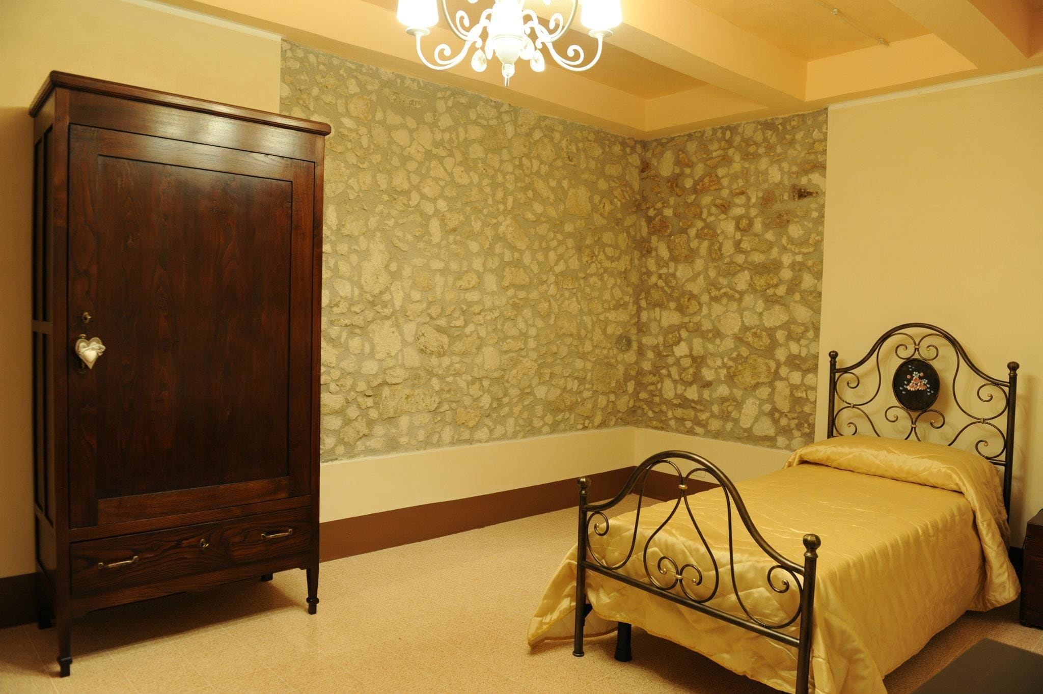 Quarto com uma cama, um guarda-roupa e uma parede de pedra.