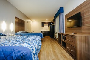 Quarto de hotel com duas camas, uma mesa, televisão e um minibar.