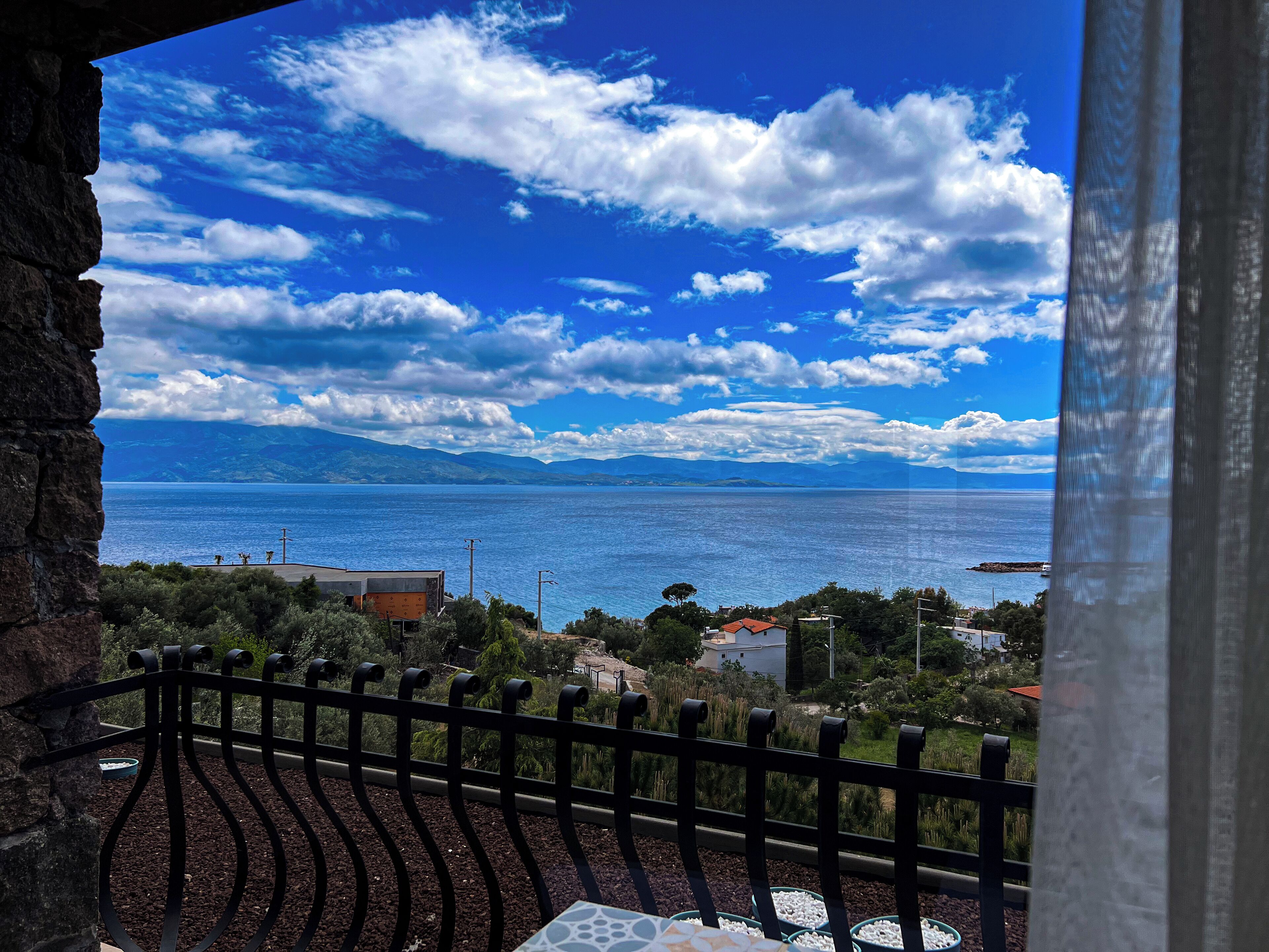 Uma varanda com vista para o mar e montanhas ao longe.