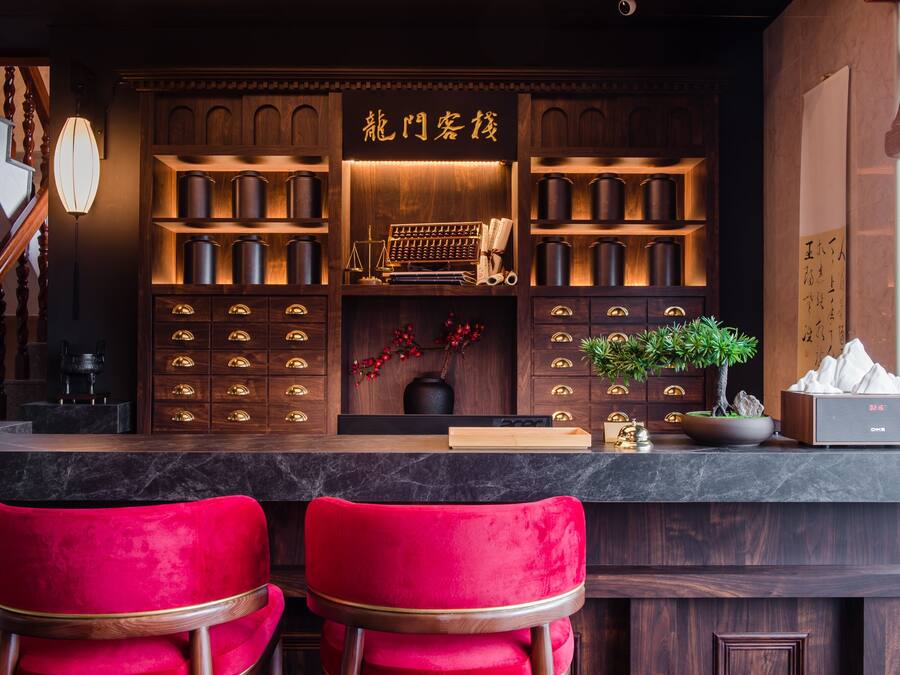 Uma área de bar com um armário de madeira exibindo vários objetos, uma balança e um vaso com planta.