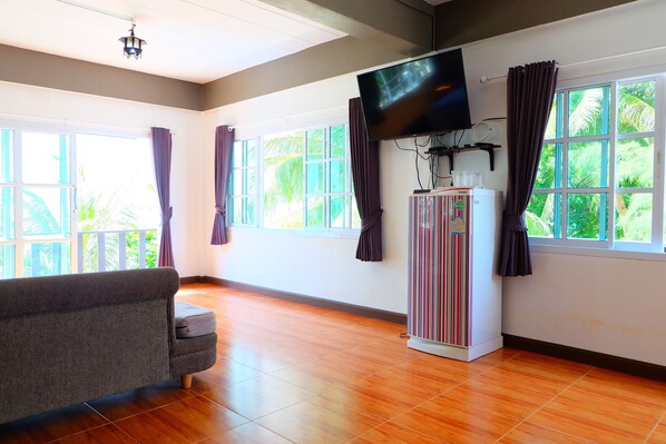 Um quarto espaçoso com sofá, televisão fixada na parede e um armário.