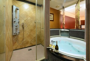 Uma casa de banho com chuveiro em cabine de vidro, hidromassagem e uma garrafa de champanhe no balcão.