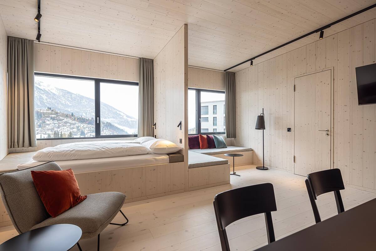 Quarto moderno com cama, área de estar e televisão.