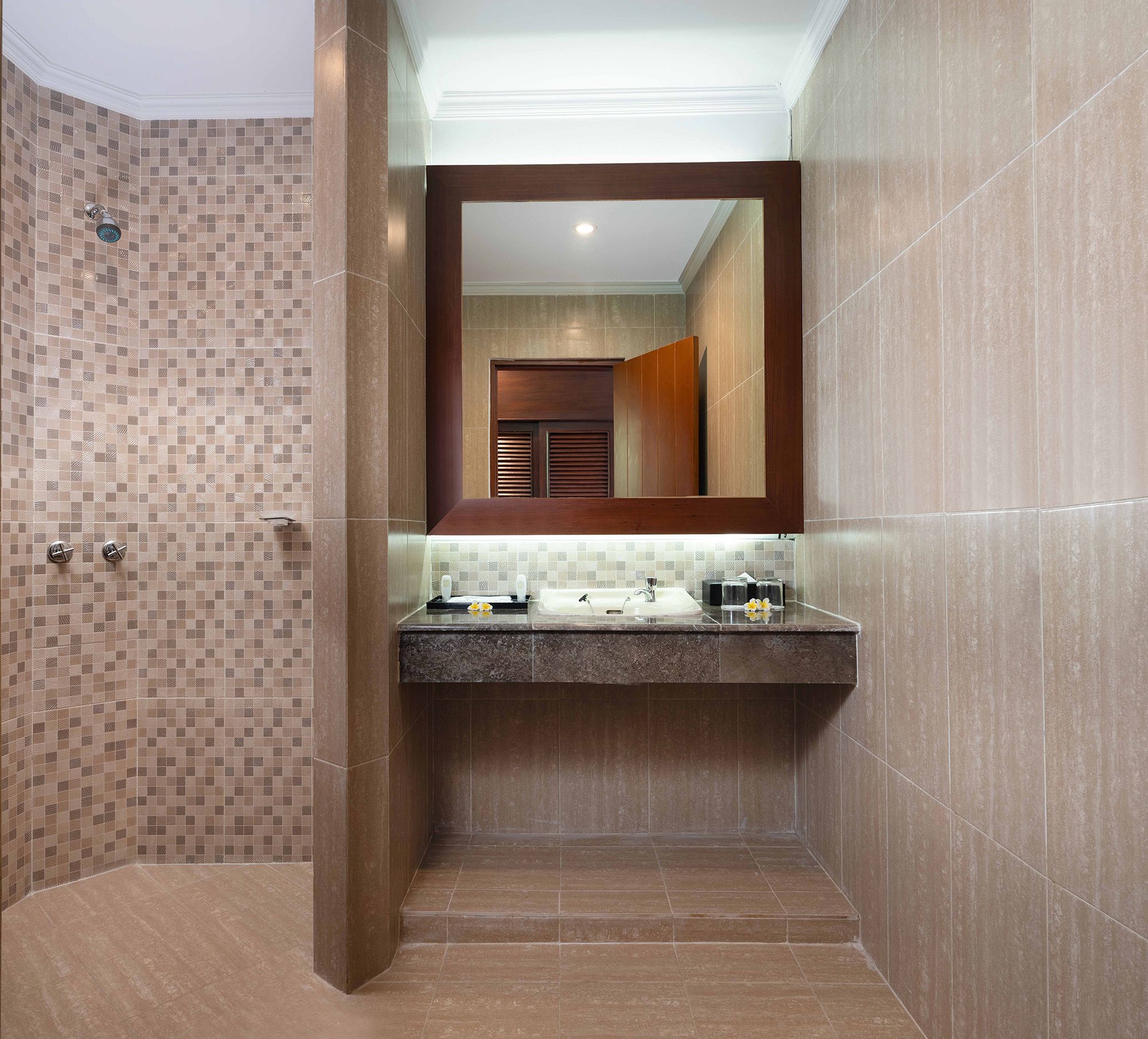 Um banheiro moderno com chuveiro, pia com espelho e paredes revestidas de azulejos.
