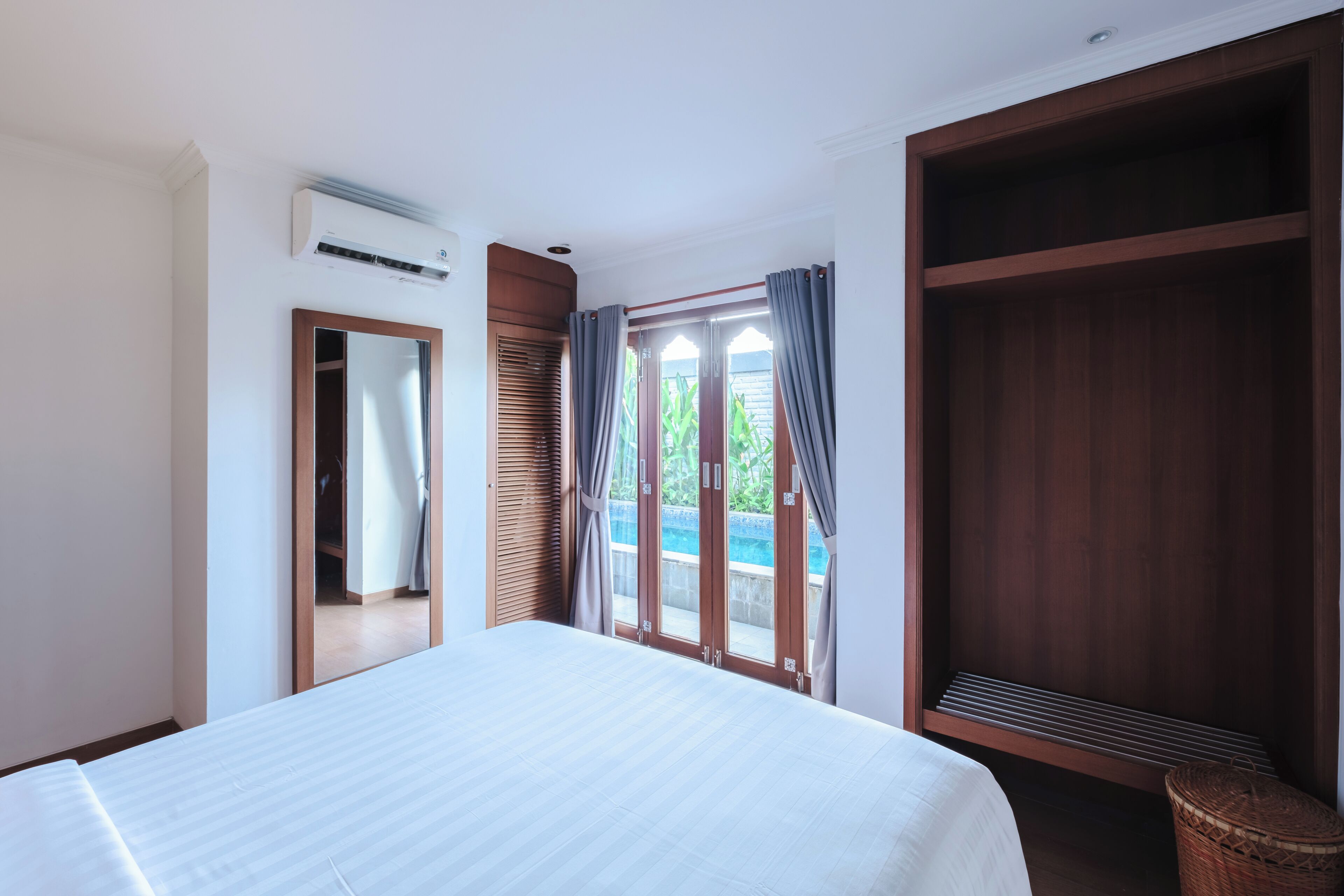 Quarto de hotel com cama, unidade de ar condicionado, guarda-roupa e vista para o exterior.