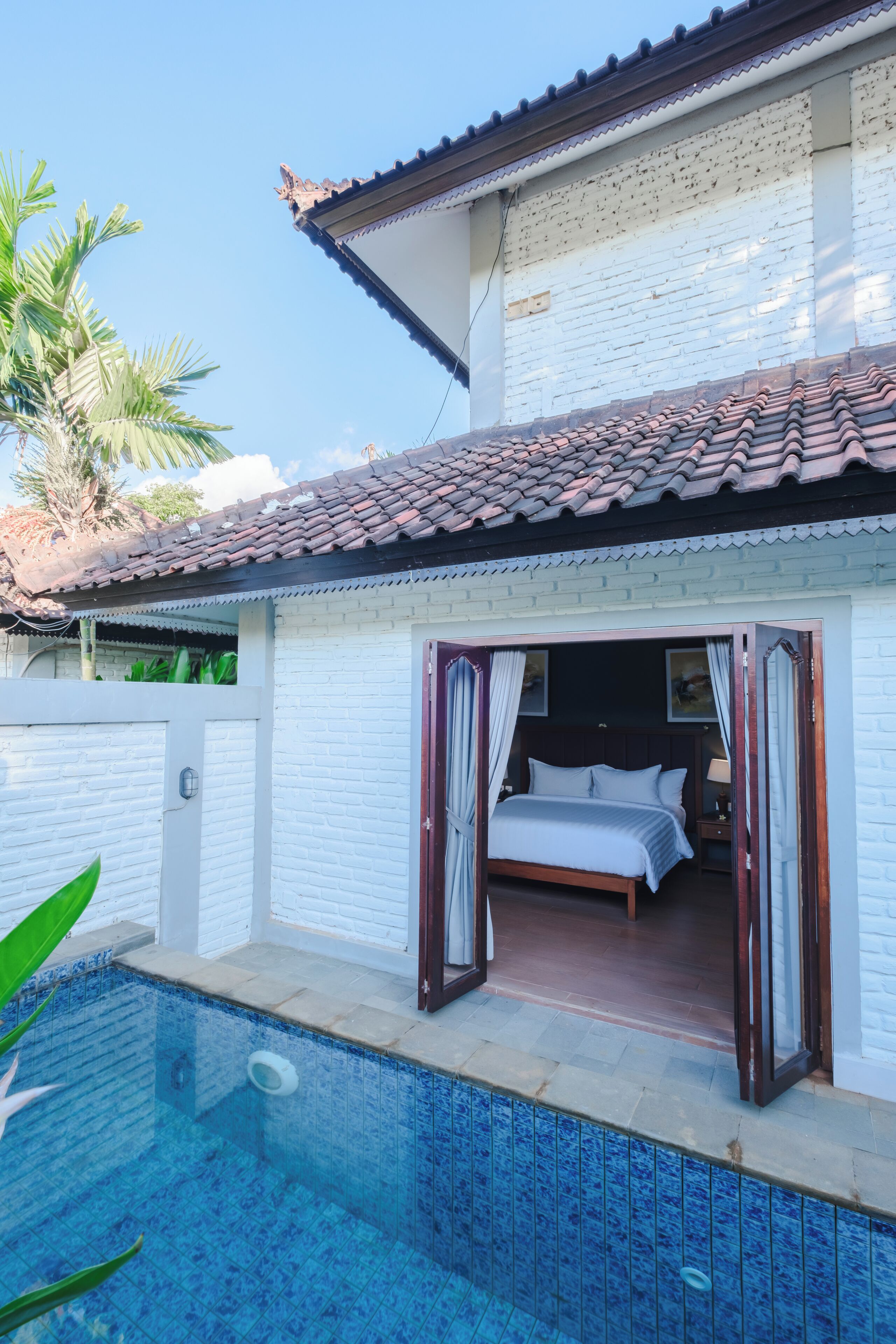 Quarto de hotel com piscina, cama e vista para o exterior.