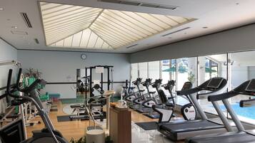 Academia com esteiras, aparelhos de musculação e um amplo claraboia.