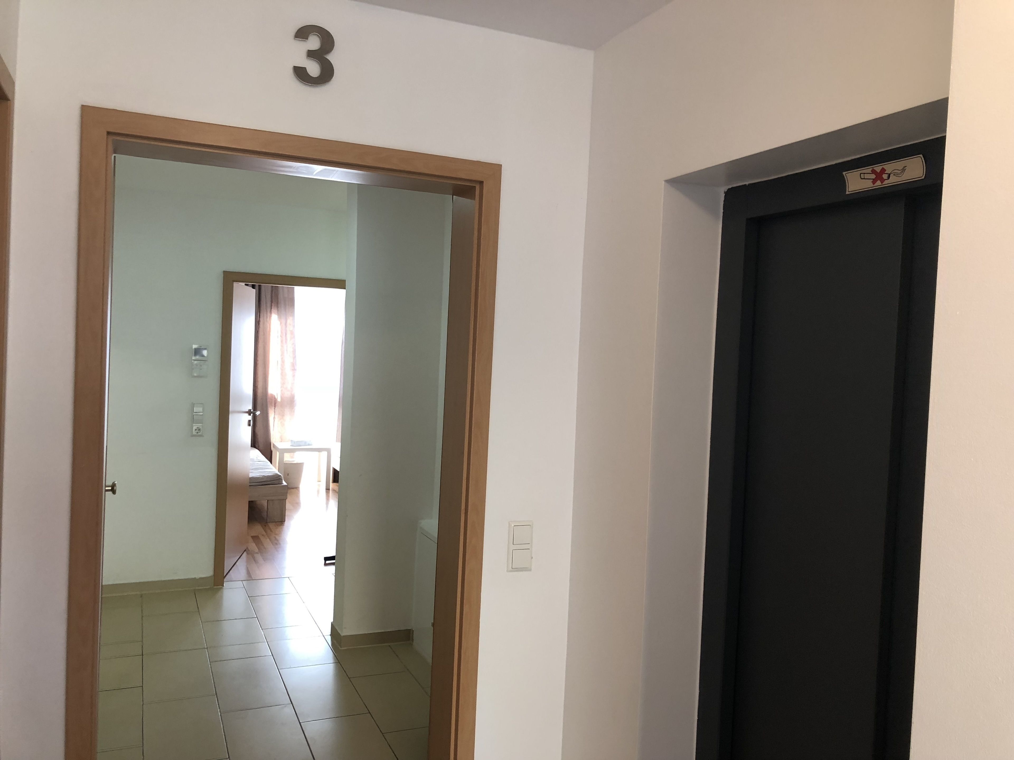 Corredor com porta marcada '3', piso de azulejos e vista para outro quarto.