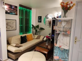 Sala de estar com sofá, mesa de centro e vitrine de vidro com roupas.