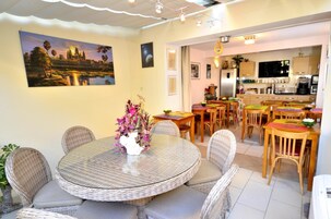 Uma área de refeições com móveis de vime, uma mesa de vidro e um vaso decorativo.