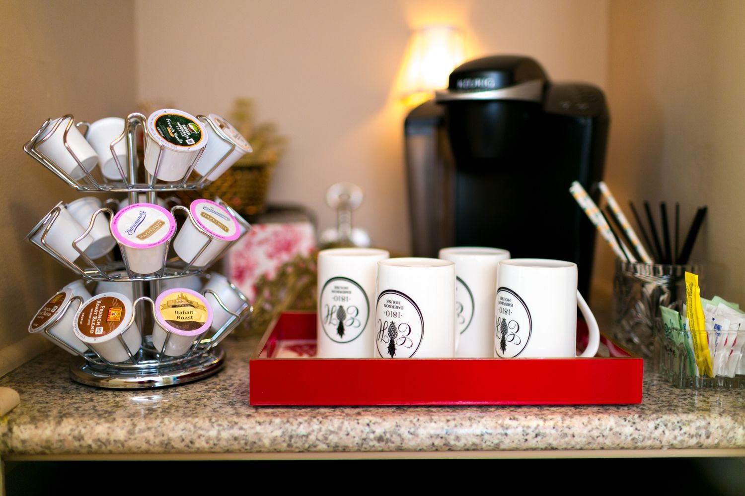Uma estação de café com cafeteira, bandeja de xícaras e dispensador de café.