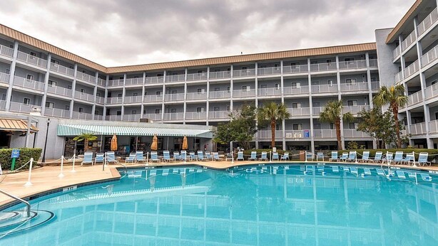 Hotel com uma grande piscina ao ar livre, várias varandas e área de estar coberta.