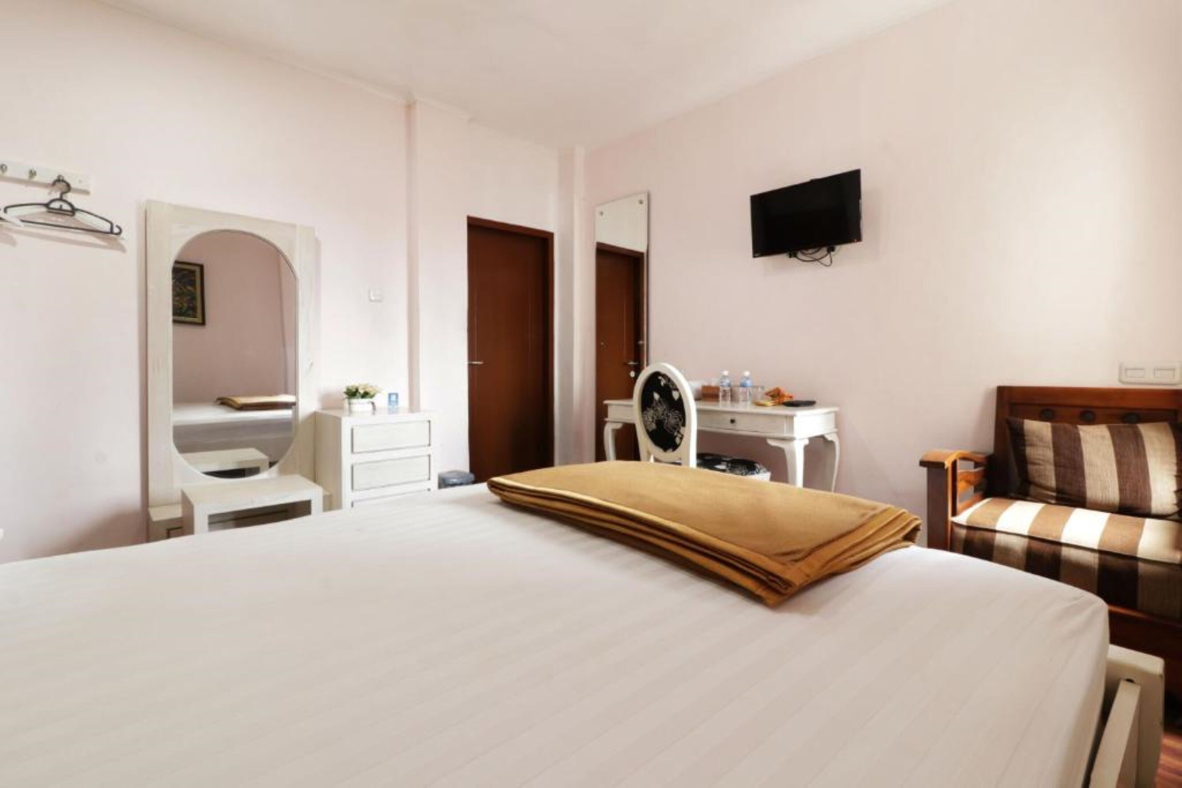 Quarto de hotel com cama, escrivaninha, cadeira, televisão na parede e janela.