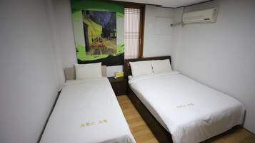 Quarto com duas camas de solteiro, uma grande pintura na parede, janela com persianas e um aparelho de ar condicionado.