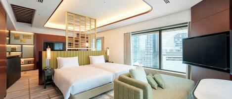 Quarto de hotel com duas camas, um sofá, uma televisão e vista para a cidade.