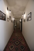 Um corredor com quadros nas paredes, um tapete estampado e uma escada no final.