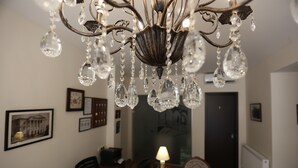 Um candelabro com detalhes em cristal em um quarto com mesa de jantar, cadeiras e quadros nas paredes.