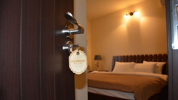 Quarto de hotel com cama, mesa de cabeceira, abajur e luminária na parede.
