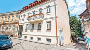 Um edifício com várias janelas, uma varanda com grades e uma porta.