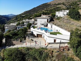 Um bairro residencial em encosta com casas modernas, uma piscina e um caminho de pedra.