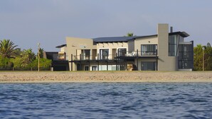 Um hotel moderno à beira-mar, com varanda, grandes janelas e vista para o mar.