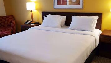 Uma cama bem arrumada com lençóis brancos, cabeceira de madeira e luminária de cabeceira.
