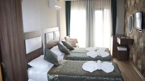 Quarto de hotel com duas camas, televisão, telefone e secretária com espelho.