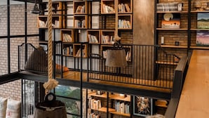 Uma biblioteca em vários níveis, com estantes de livros, um balanço de corda e vista para o exterior.