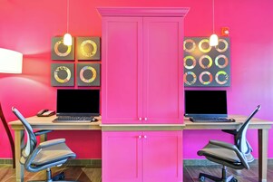 Quarto com duas mesas, cada uma com um laptop e um telefone, e duas cadeiras de escritório.