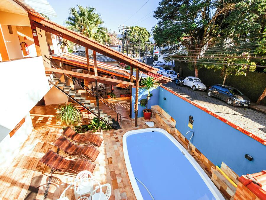 Piscina no terraço com água azul, deck de madeira e mobiliário para área externa.