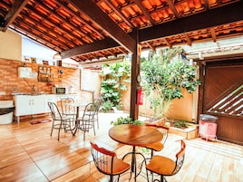 Um pátio com mesa e cadeiras de madeira, uma parede de tijolos e um vaso de planta.