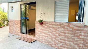 Um edifício com entrada por porta de vidro, um vaso de planta e uma janela com persiana fechada.