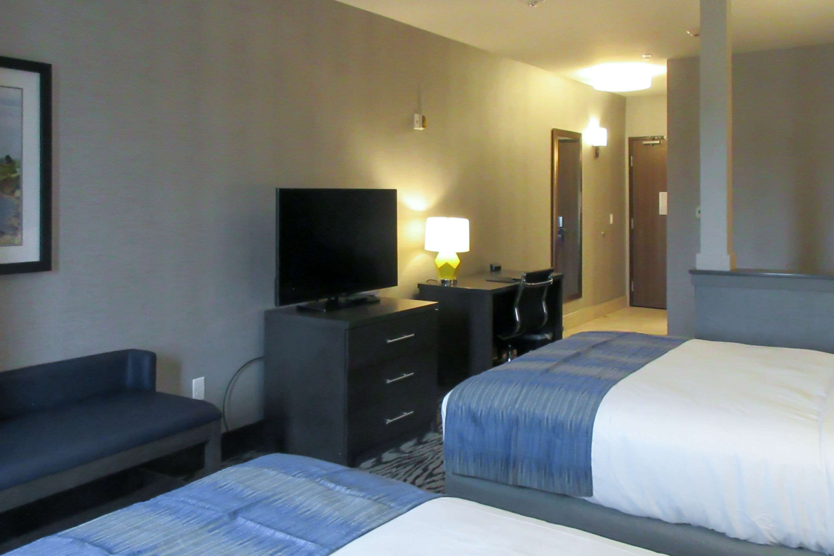 Quarto de hotel com duas camas, uma televisão, uma mesa e uma cadeira.