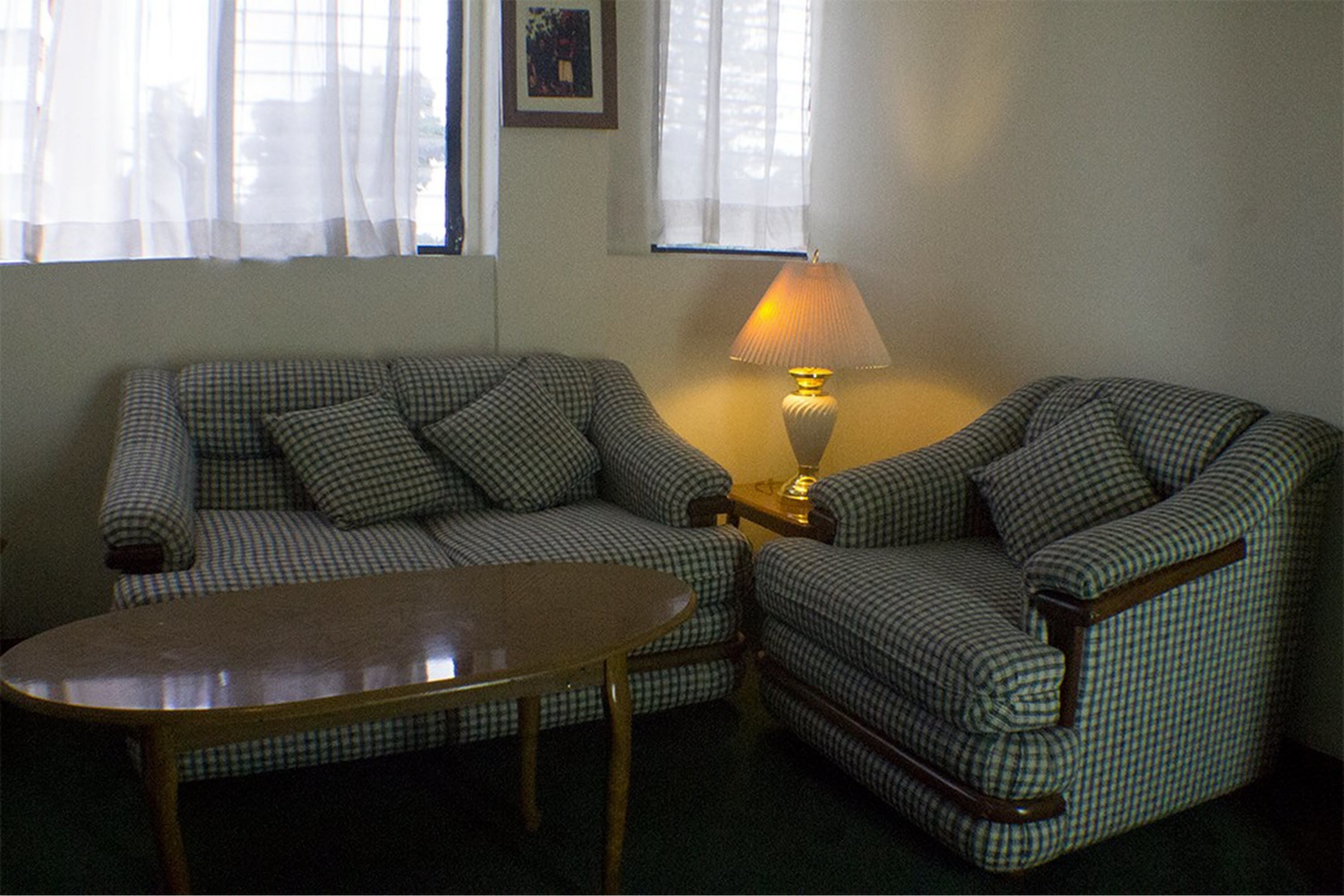 Um quarto com um sofá xadrez, uma poltrona a combinar e uma mesa de centro de madeira.