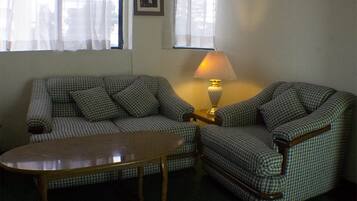 Um quarto com um sofá xadrez, uma poltrona a combinar e uma mesa de centro de madeira.