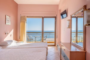 Quarto de hotel com varanda, cama, penteadeira e televisão.