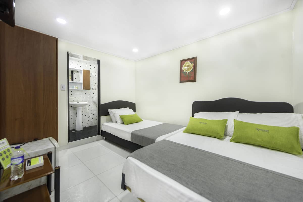 Quarto de hotel com duas camas, banheiro e guarda-roupa de madeira.
