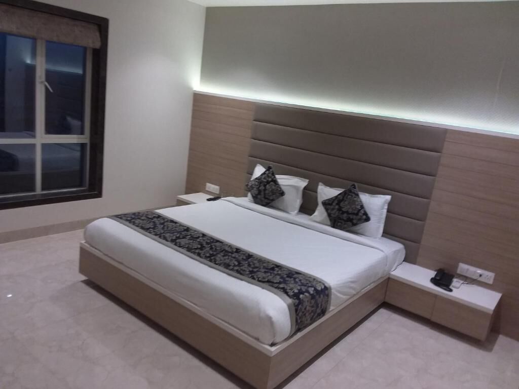 Quarto moderno com uma cama grande, mesas de cabeceira e uma janela.