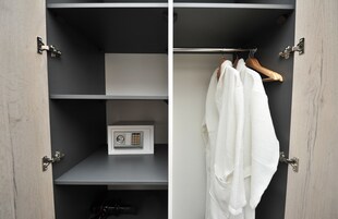 Um guarda-roupa com várias prateleiras, uma barra para pendurar roupas e um pequeno aparelho eletrônico em uma das prateleiras.
