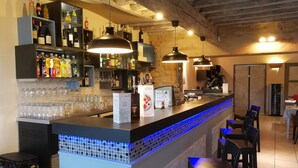 Uma área de bar com prateleiras de garrafas de bebidas, copos e um suporte para cardápio.