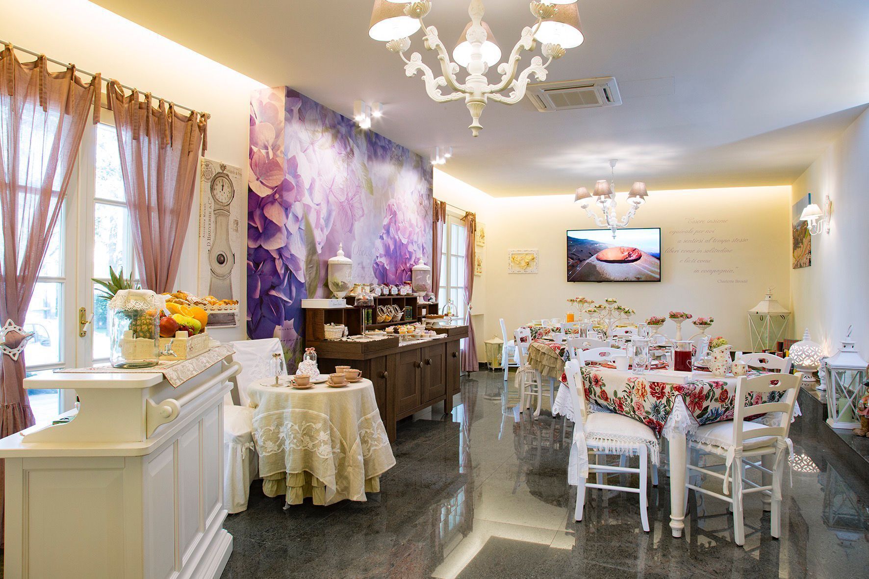Uma sala de jantar com um grande mural floral, um lustre e um buffet.