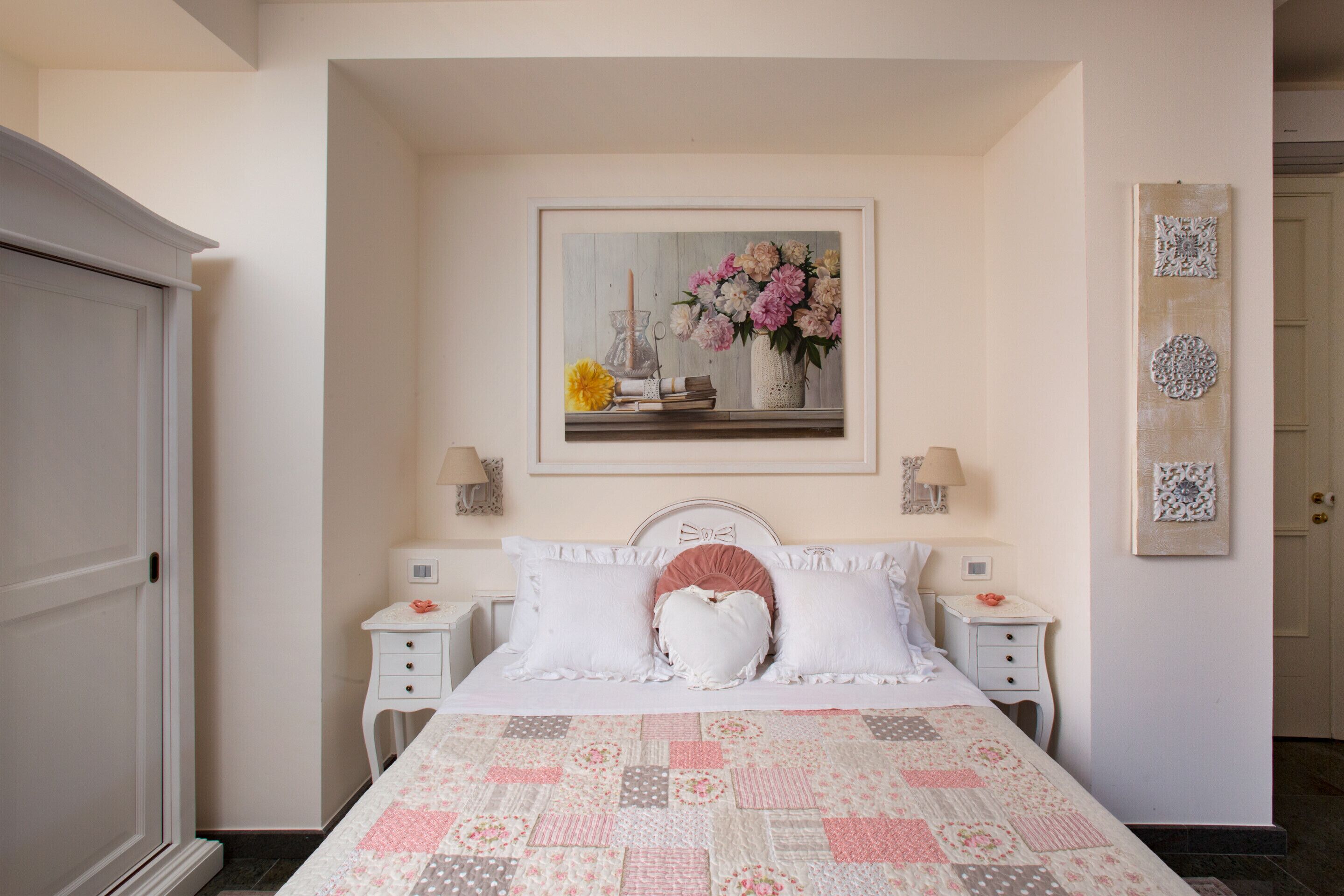 Quarto bem arrumado com cama, mesas de cabeceira e um quadro na parede.