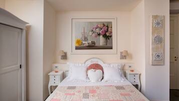 Quarto bem arrumado com cama, mesas de cabeceira e um quadro na parede.