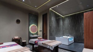 Um spa moderno com mesa de massagem, um espelho grande, uma banheira e um pequeno lavatório com pia.