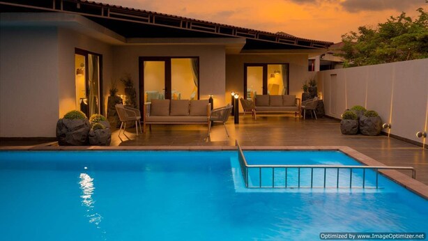 Uma área de piscina moderna com espaço para sentar integrado e um alpendre coberto.