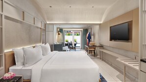 Quarto de hotel com uma cama grande, televisão, escrivaninha e vista para o exterior.