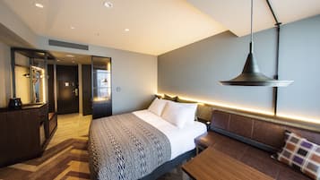 Quarto de hotel moderno com uma cama grande, um banco de madeira, uma escrivaninha e um espelho.