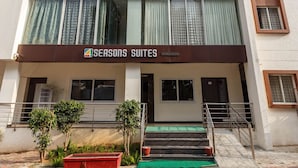 A building with a sign reading "Seasons Suites" and a staircase leading to the entrance.