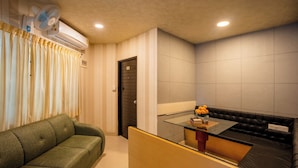Uma sala de estar moderna com um sofá verde, uma mesa de centro de vidro e um sofá de couro preto.
