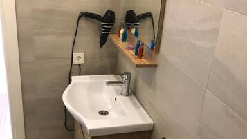Casa de banho com lavatório, espelho, secador de cabelo e porta-toalhas.